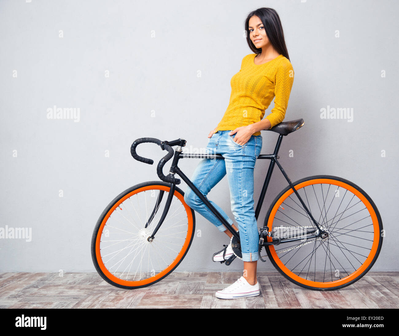 Full length portrait of a happy casual woman standing with bicycle on ...