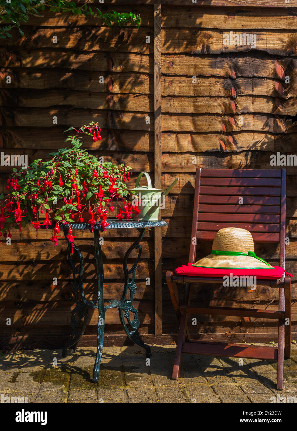 Ladies Straw Hat and Wooden Garden Chair with Bright Red Cushion Stock ...