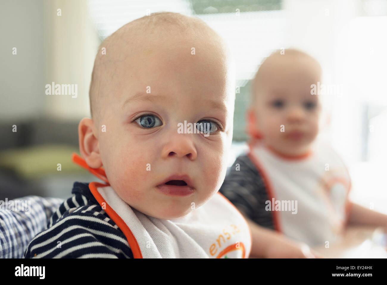 Portrait of staring baby twin brothers in high chairs Stock Photo - Alamy
