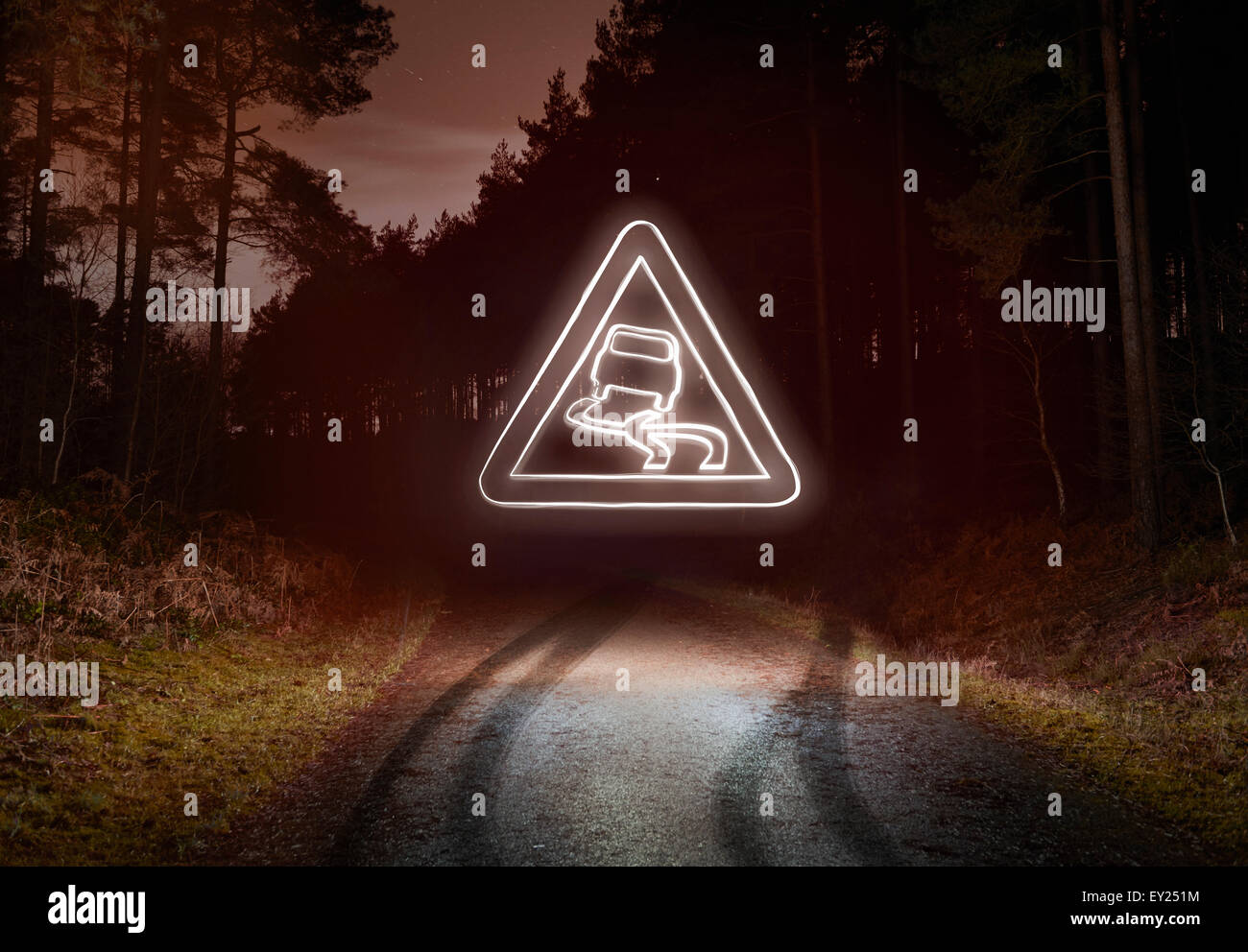 Tyre skid marks and glowing slippery warning sign above forest road at ...