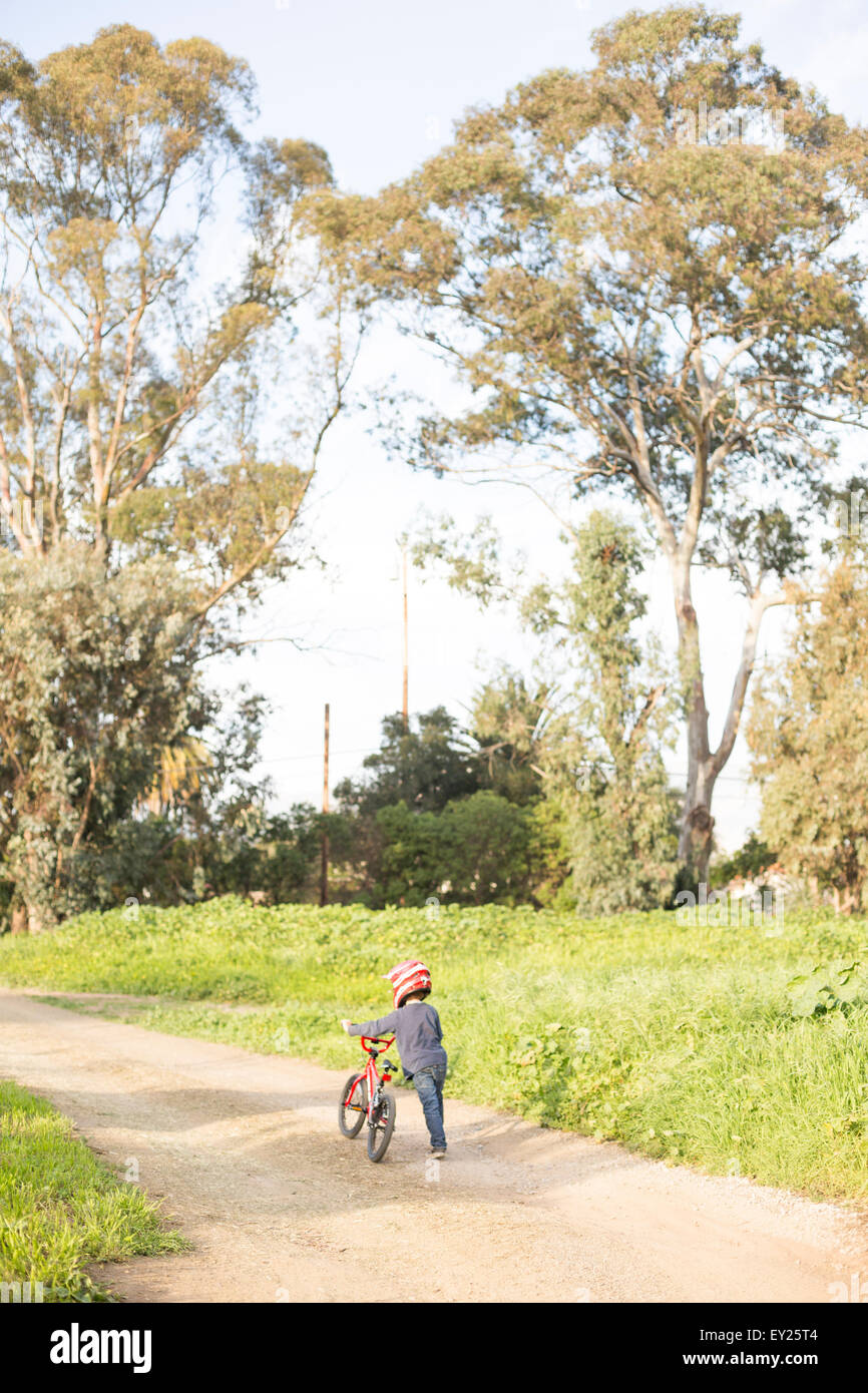 Boy pushing a bicycle on path Stock Photo - Alamy