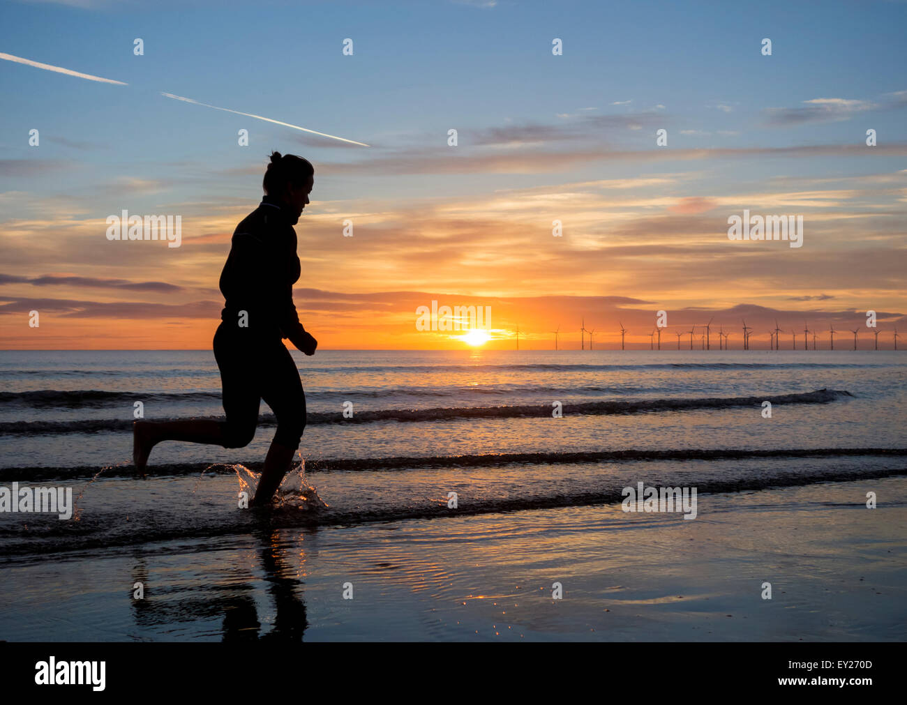 Woman running barefoot on beach at sunrise. UK Stock Photo - Alamy