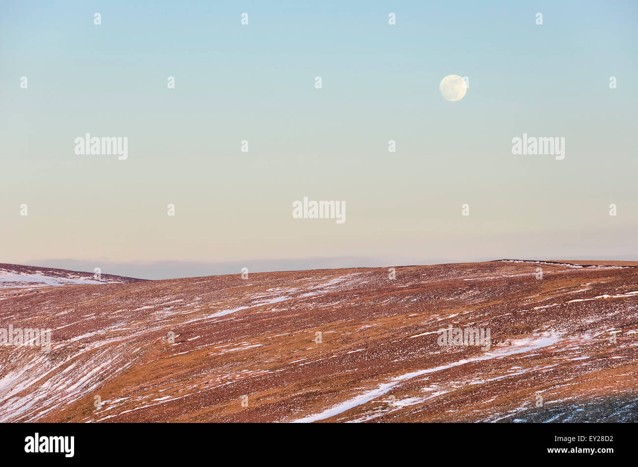 Moon rising above moorland with traces of late winter snow. Beautiful ...