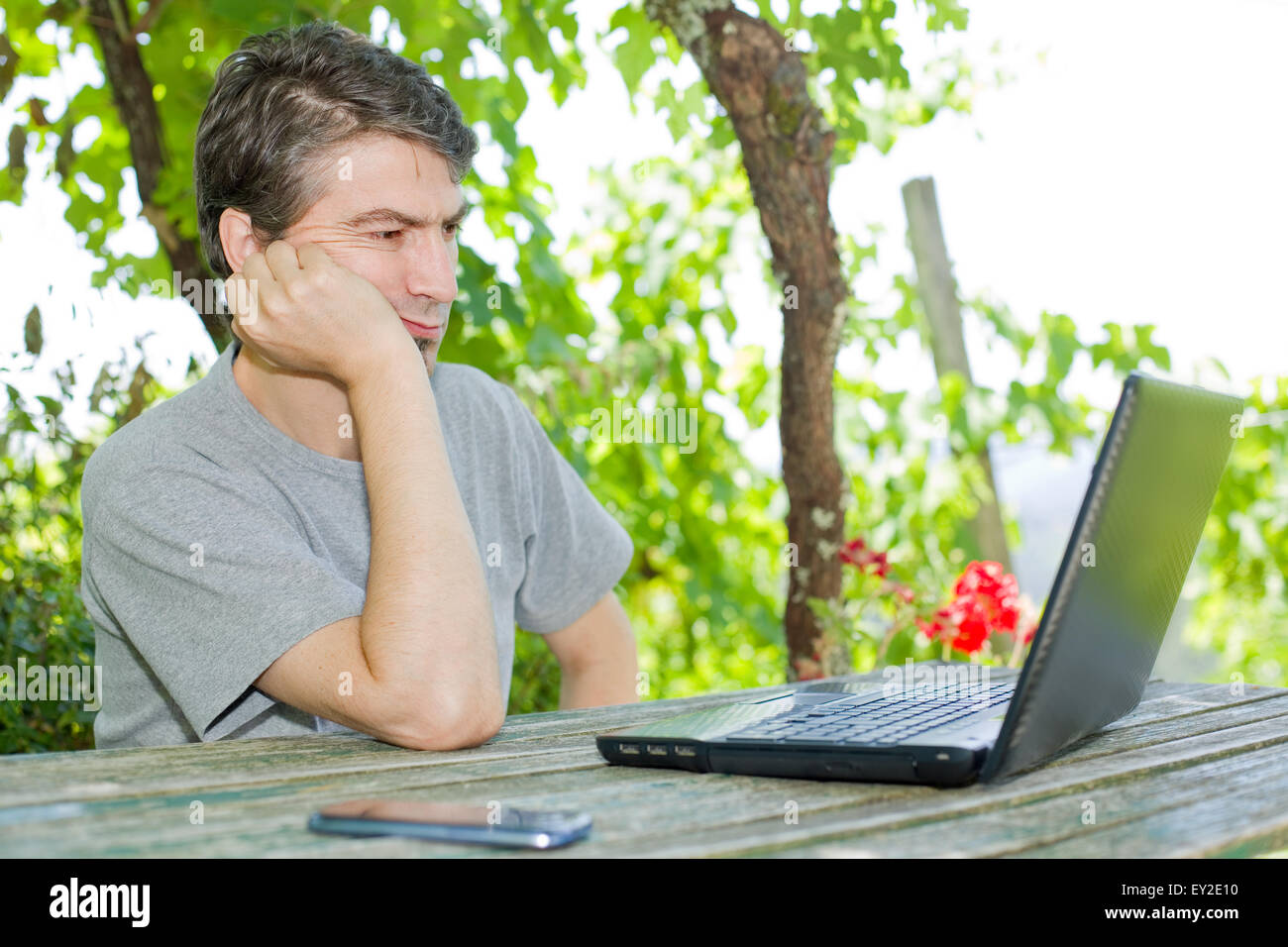 man sitting outdoor working with a laptop Stock Photo - Alamy