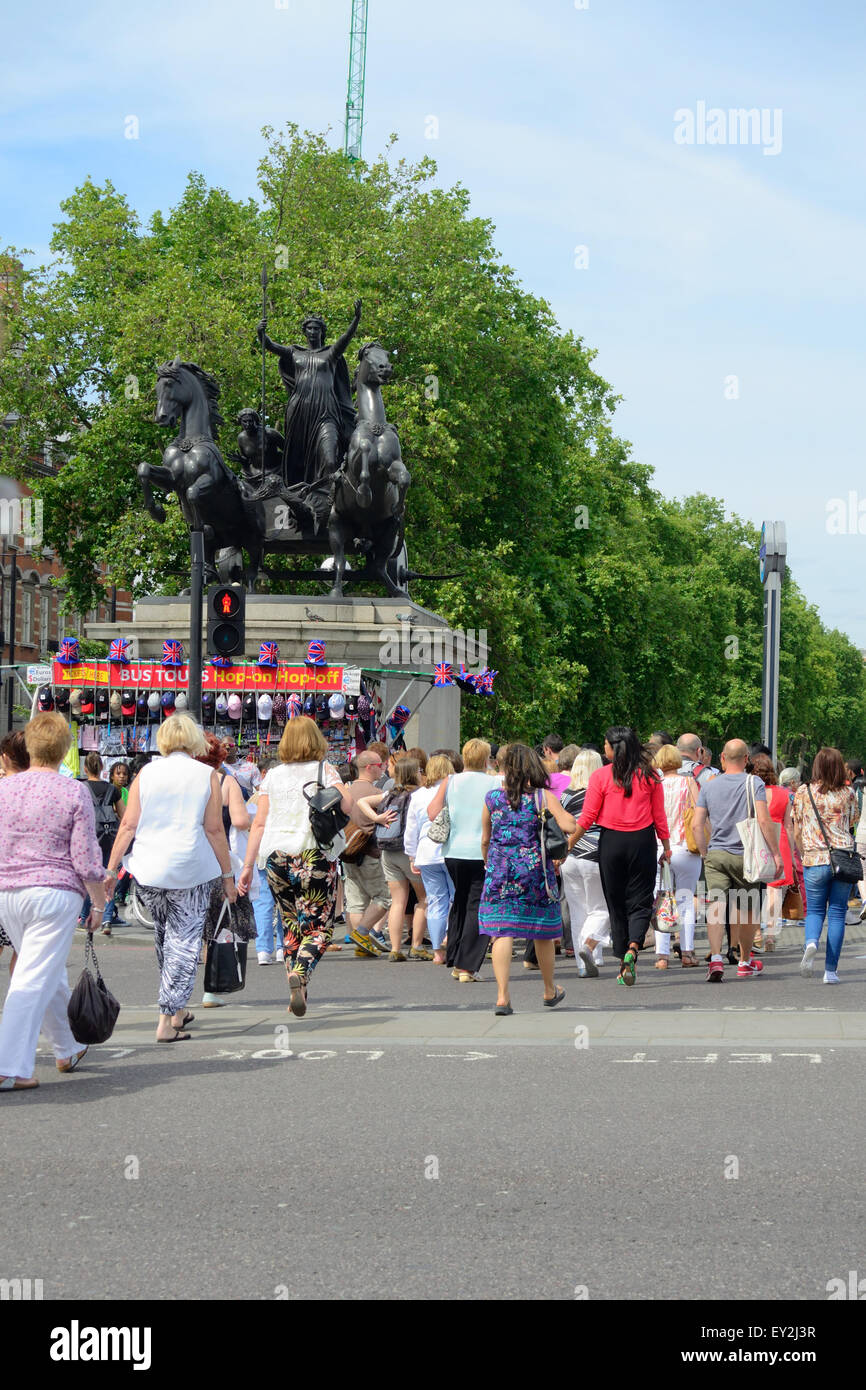 Pedestrians cross the road over Westminster Bridge beneath a statue of ...