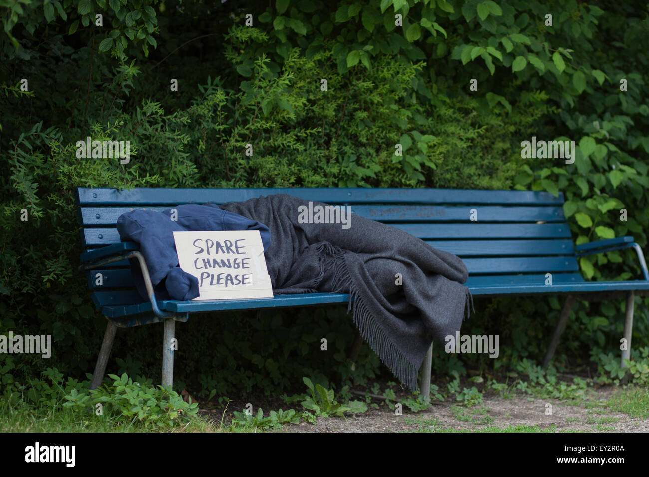 Homeless man on a park bench with a cardboard sign Stock Photo - Alamy