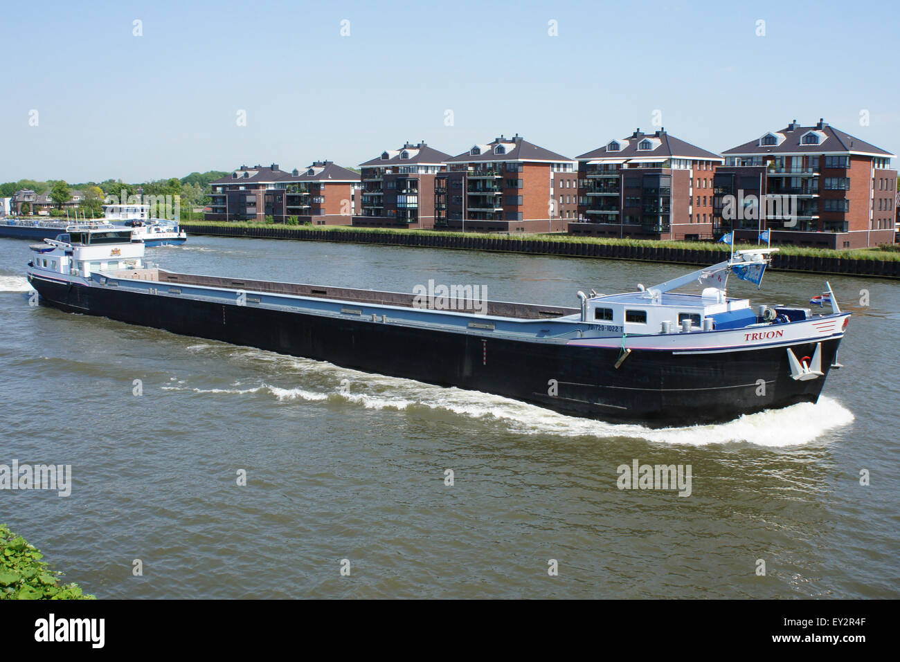 This image depicts a large container ship navigating the Amsterdam-Rijn ...