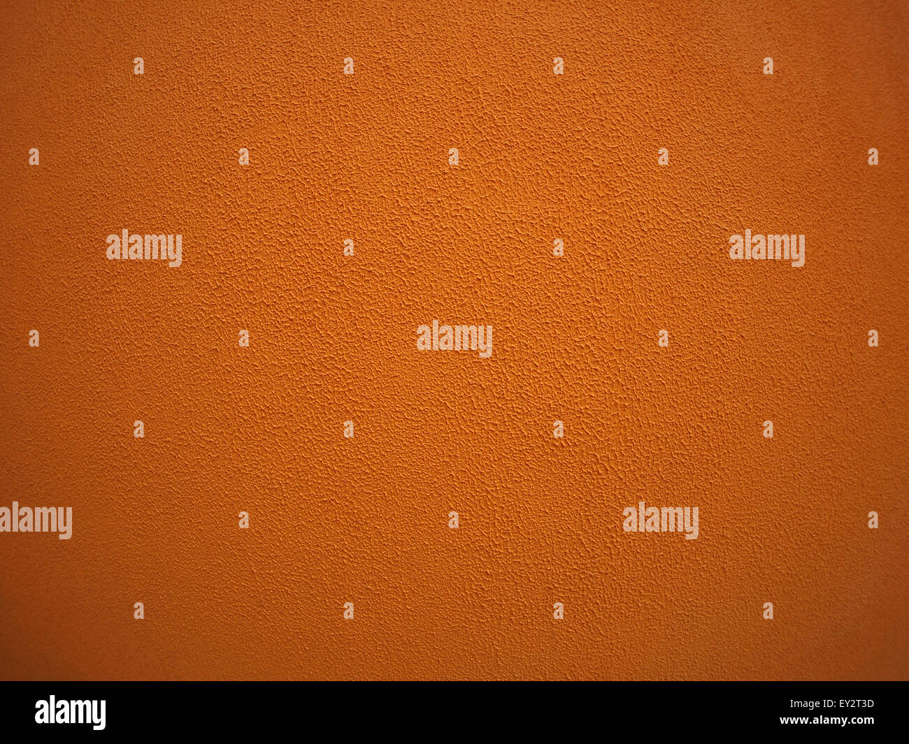 Stone wall covered with a layer of rough orange paint for the ...