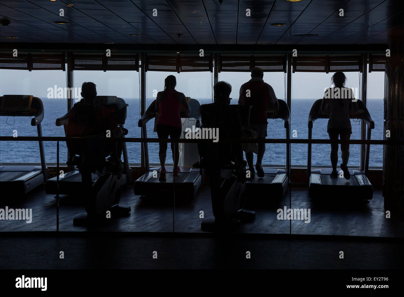 People exercising at the gym on a cruise ship in silhouette on sea ...