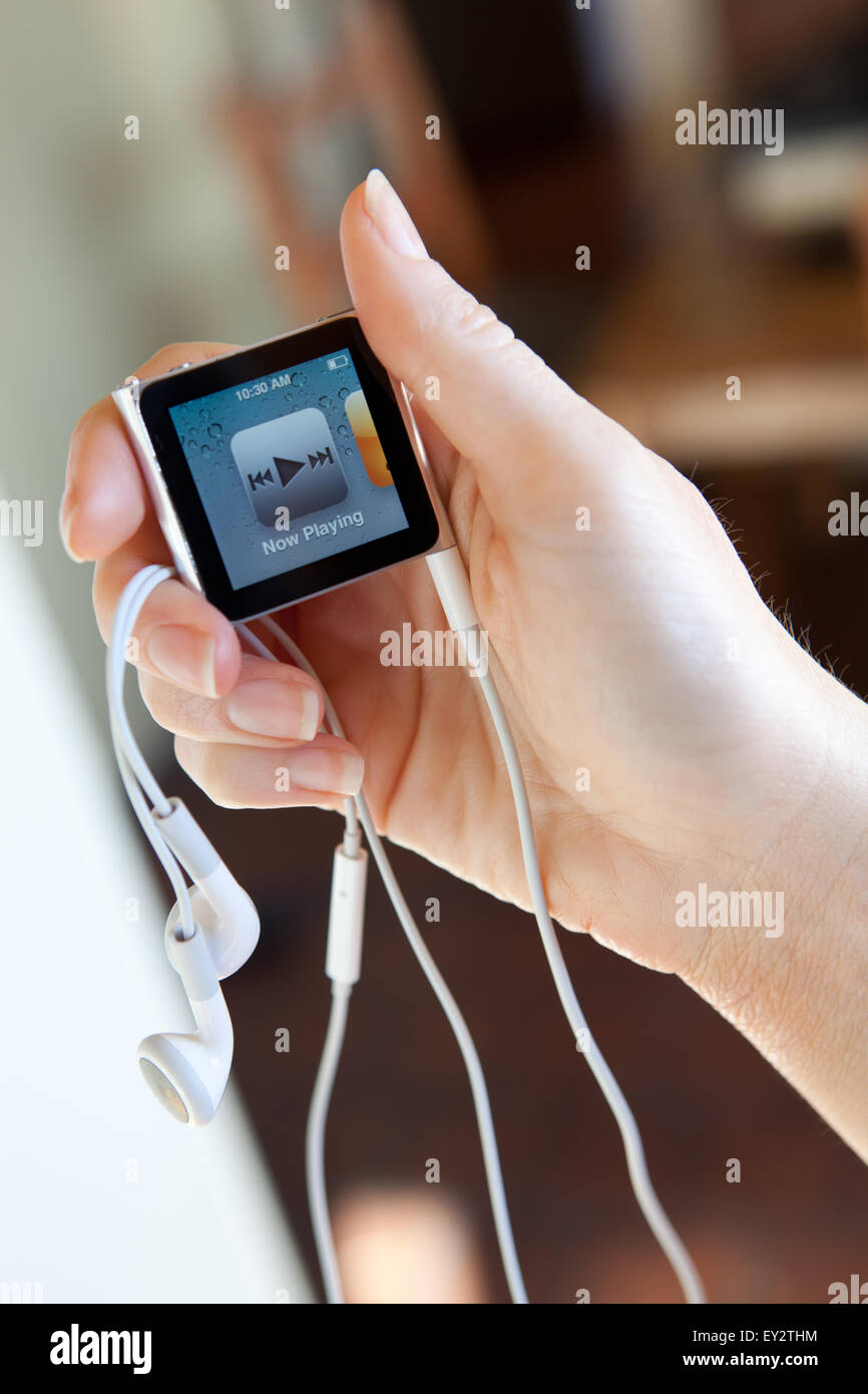 Close up of an Apple iPod nano, with headphones, held in a womans hand ...