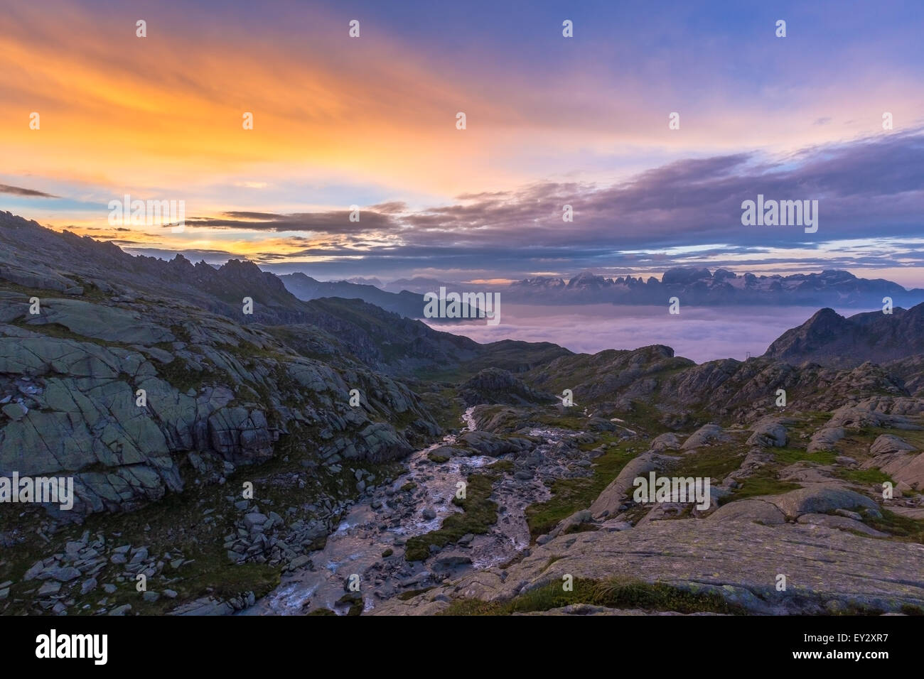Sunrise from the high Amola valley, alpine torrent. Clouds and sunlight ...