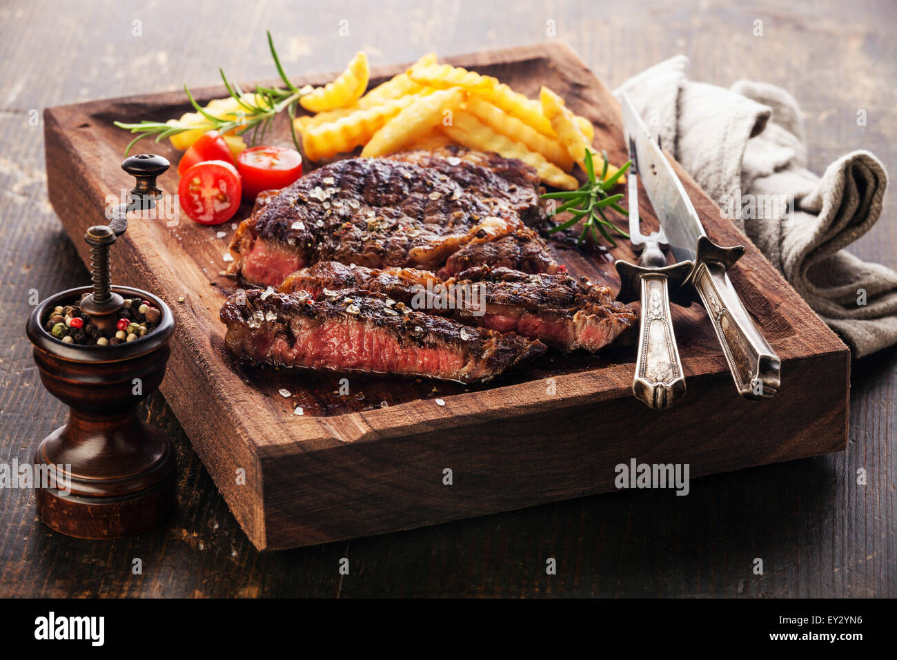 Sliced medium rare grilled Steak Ribeye with french fries on serving ...