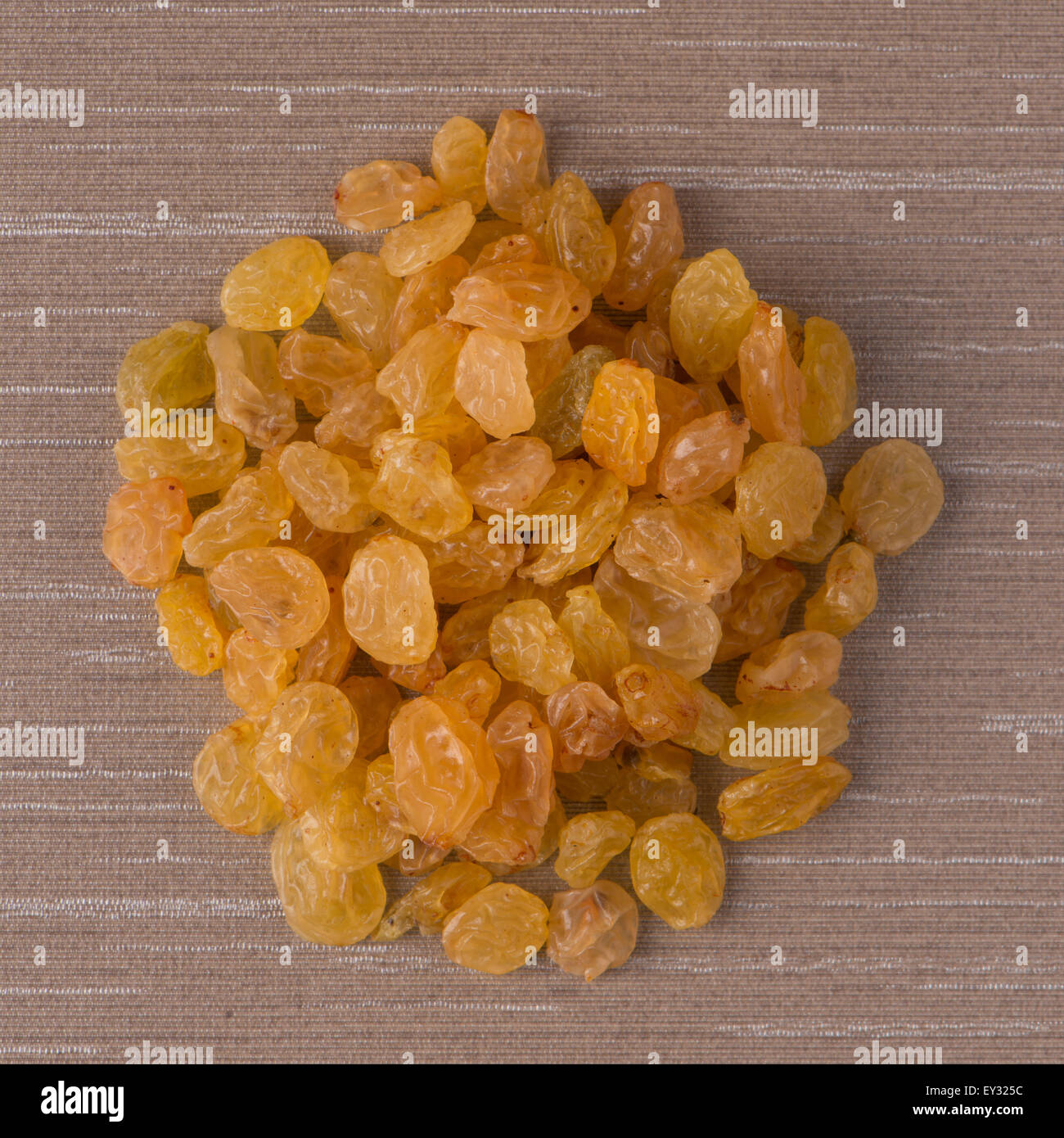 Top view of circle of golden raisins against brown vinyl background ...