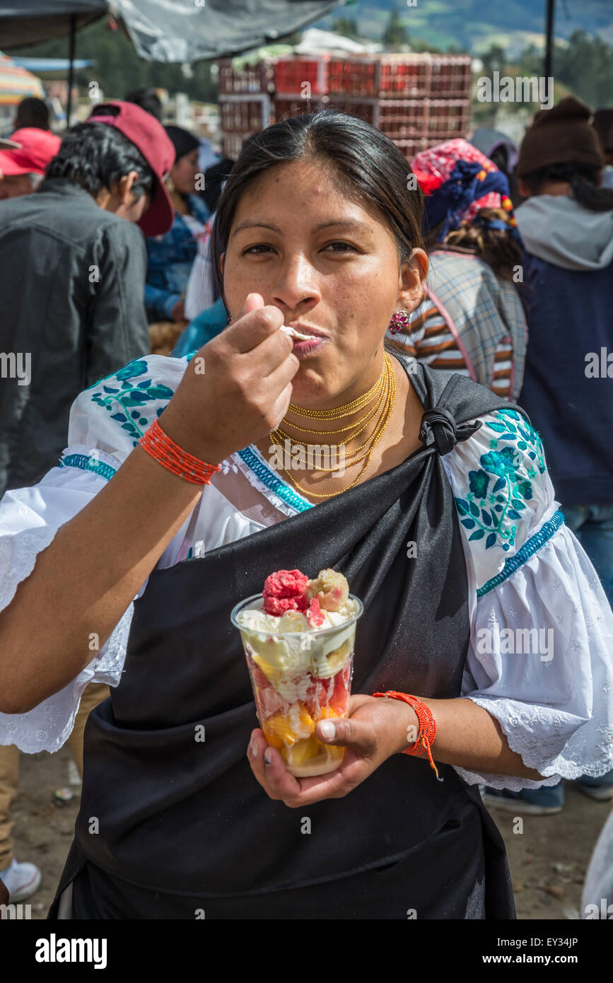 A young native woman in traditional dress enjoys an ice cream at local ...