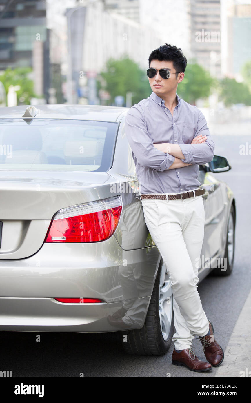 Young man leaning against his car Stock Photo - Alamy