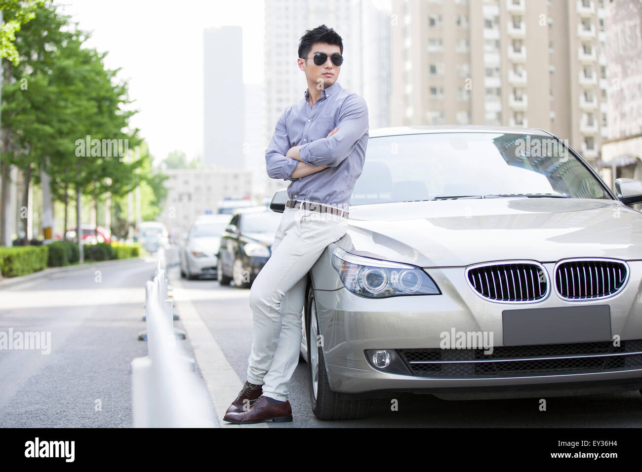 Young man leaning against his car Stock Photo - Alamy