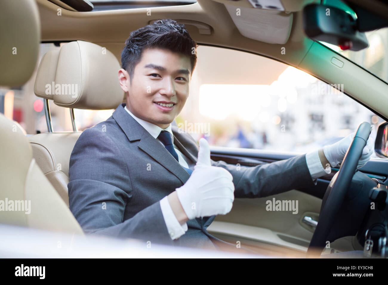 Chauffeur doing thumbs up inside car Stock Photo - Alamy
