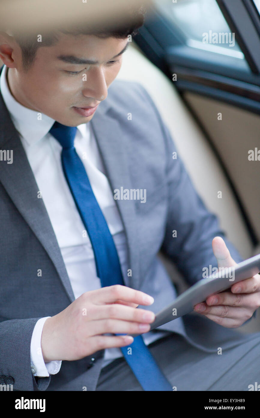 Businessman using digital tablet in car back seat Stock Photo - Alamy
