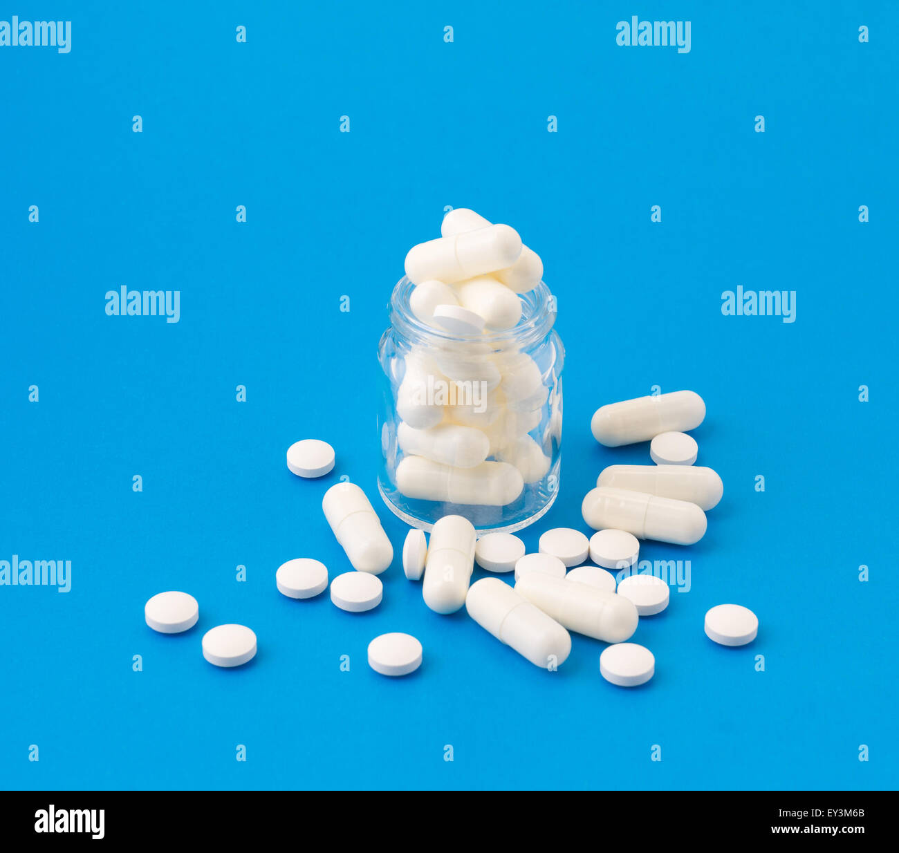 the small group of white tablets and pills is scattered on a surface ...