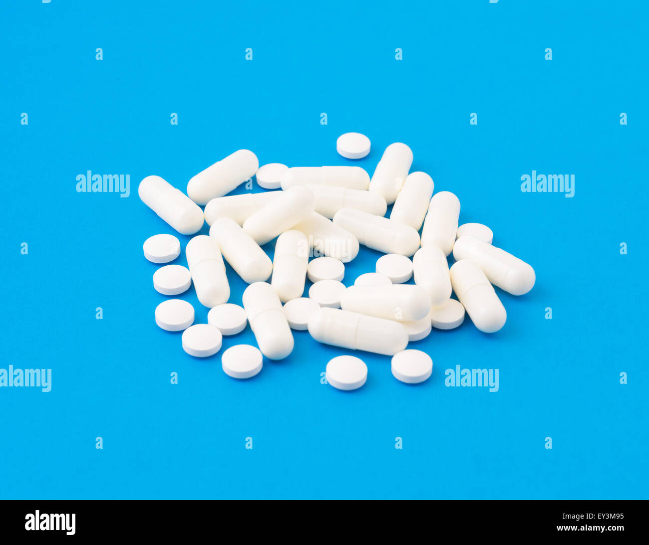 the small group of white tablets and pills is scattered on a surface ...