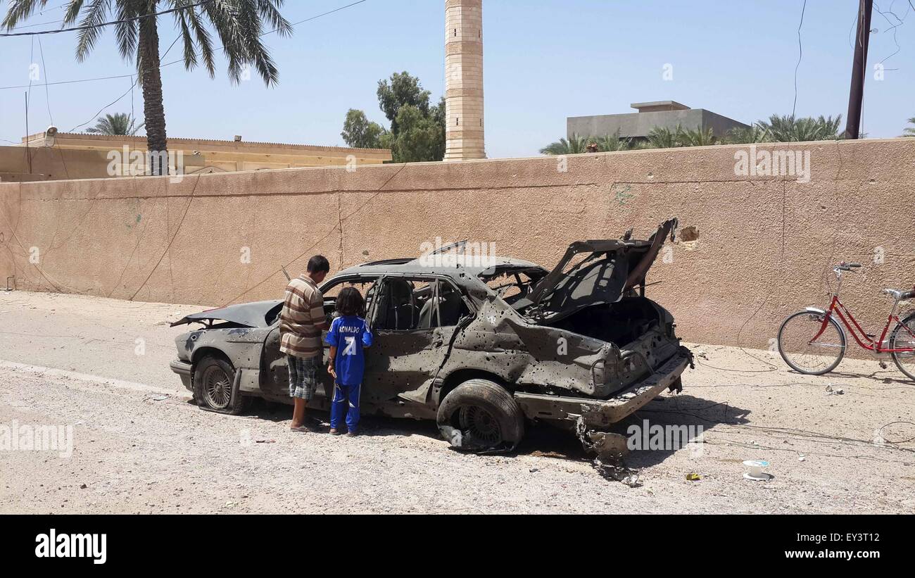 Fallujah, Iraq. 21st July, 2015. Two boys look inside a damaged car ...