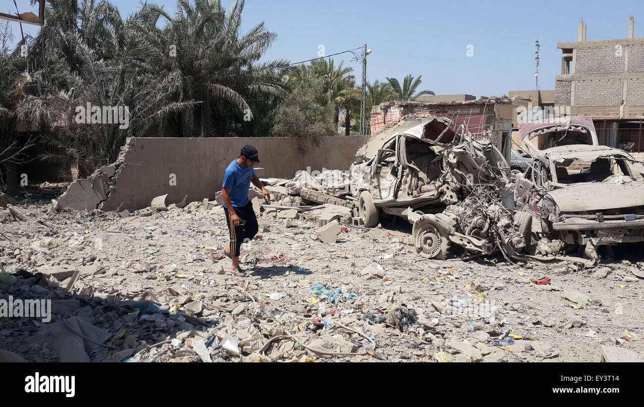 Fallujah, Iraq. 21st July, 2015. A man walks near damaged vehicles ...