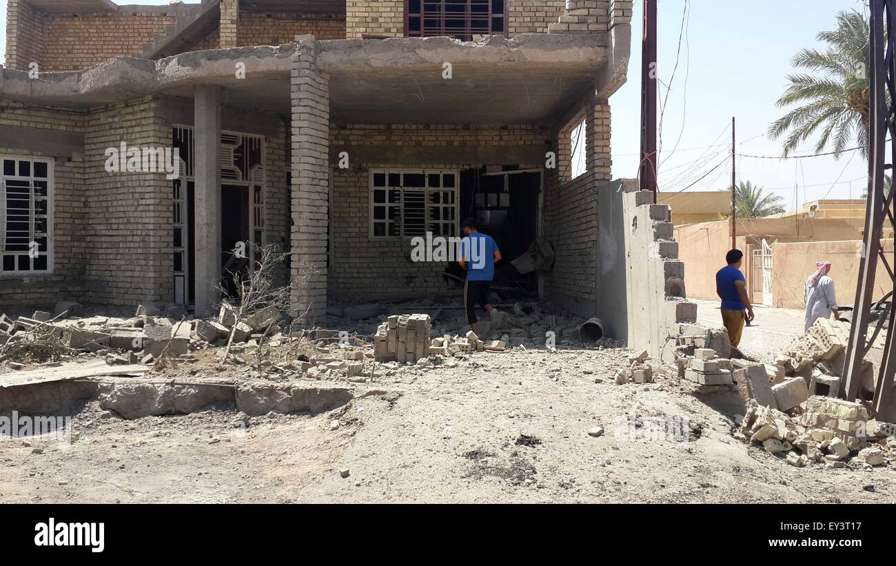 Fallujah, Iraq. 21st July, 2015. Men stand by a damaged building after ...
