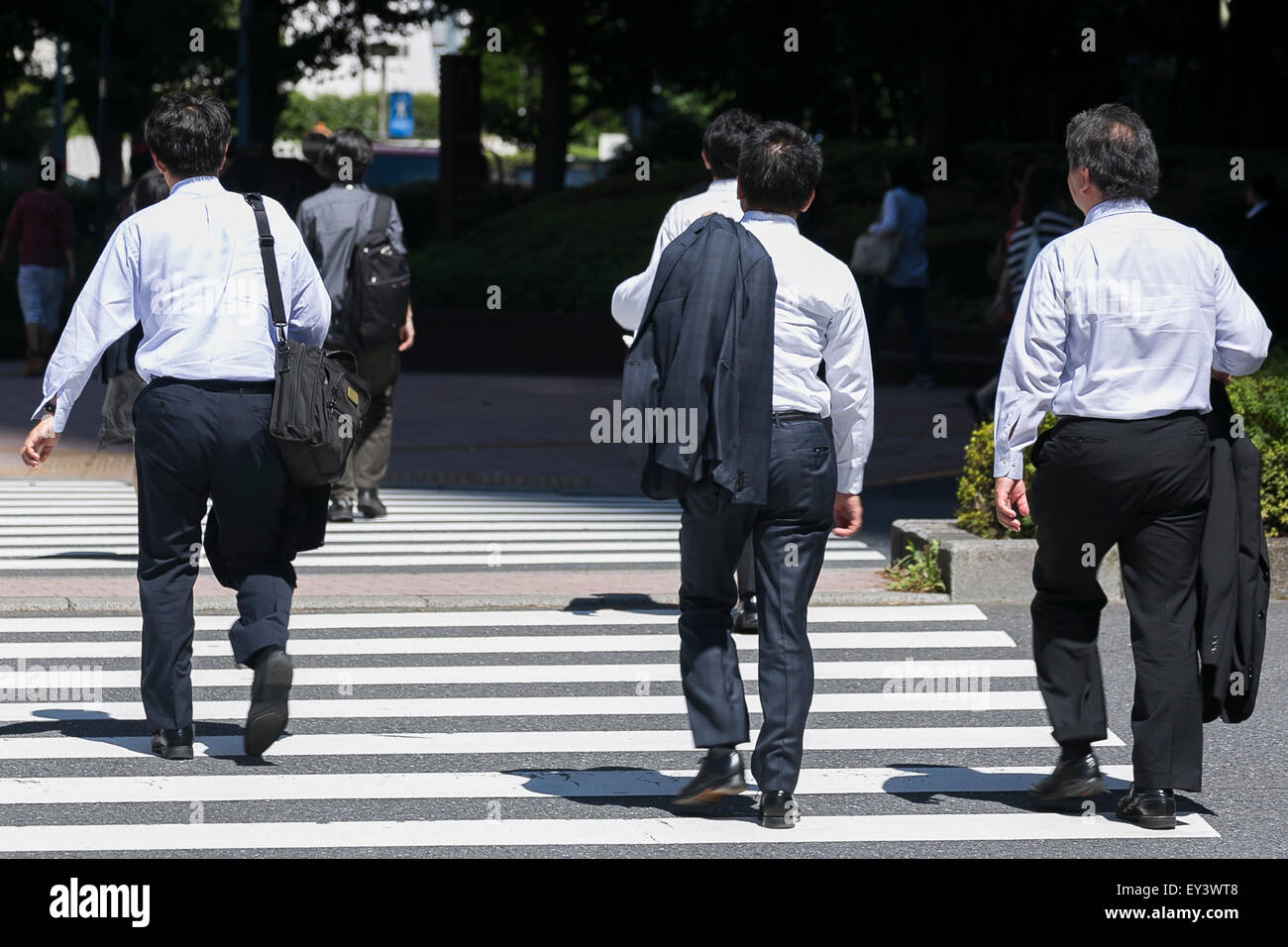 Tokyo, Japan. 21st July, 2015. Japanese office workers walk under the ...