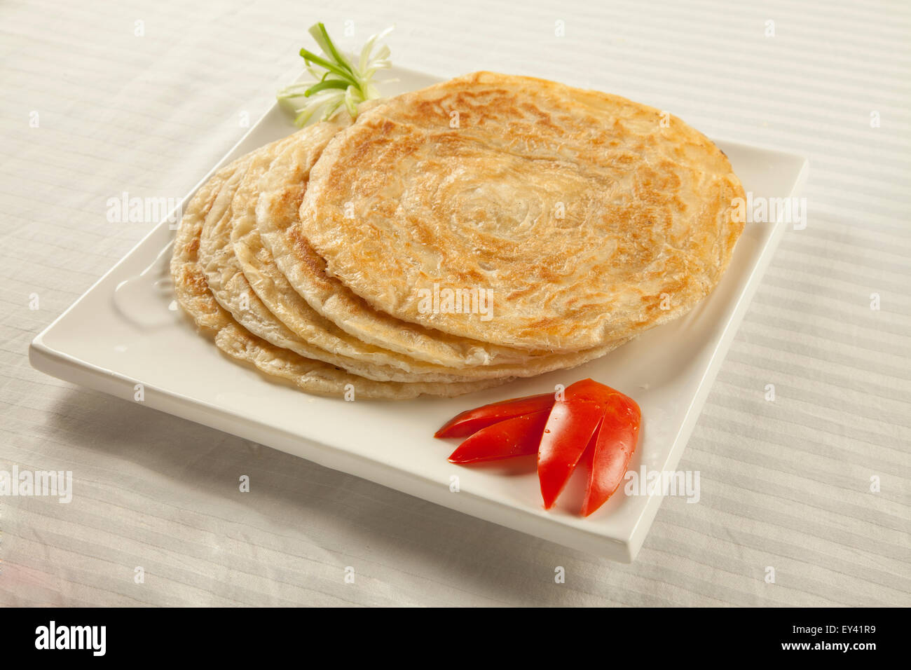 Plain paratha puri served with freshly sliced tomato and cucumber Stock ...