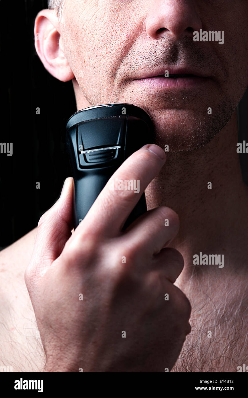 Man Shaving Face with Electric Razor Against Black Background Stock ...