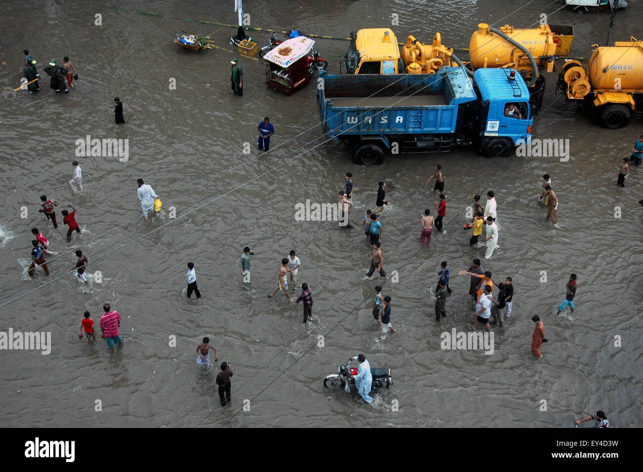 Lahore. 21st July, 2015. People wade in a flooded street after heavy ...