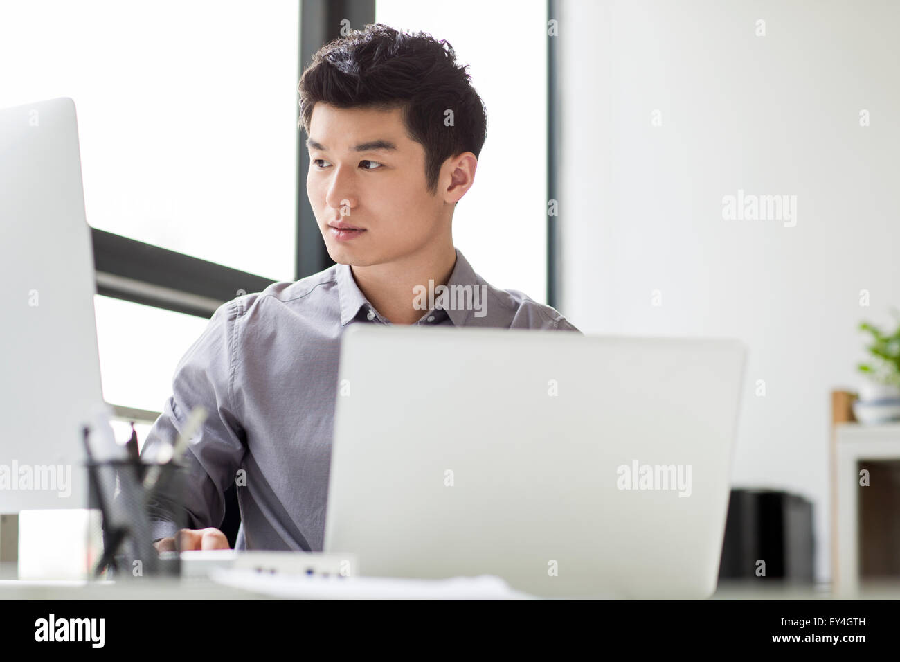 Young businessman using laptop in office Stock Photo - Alamy