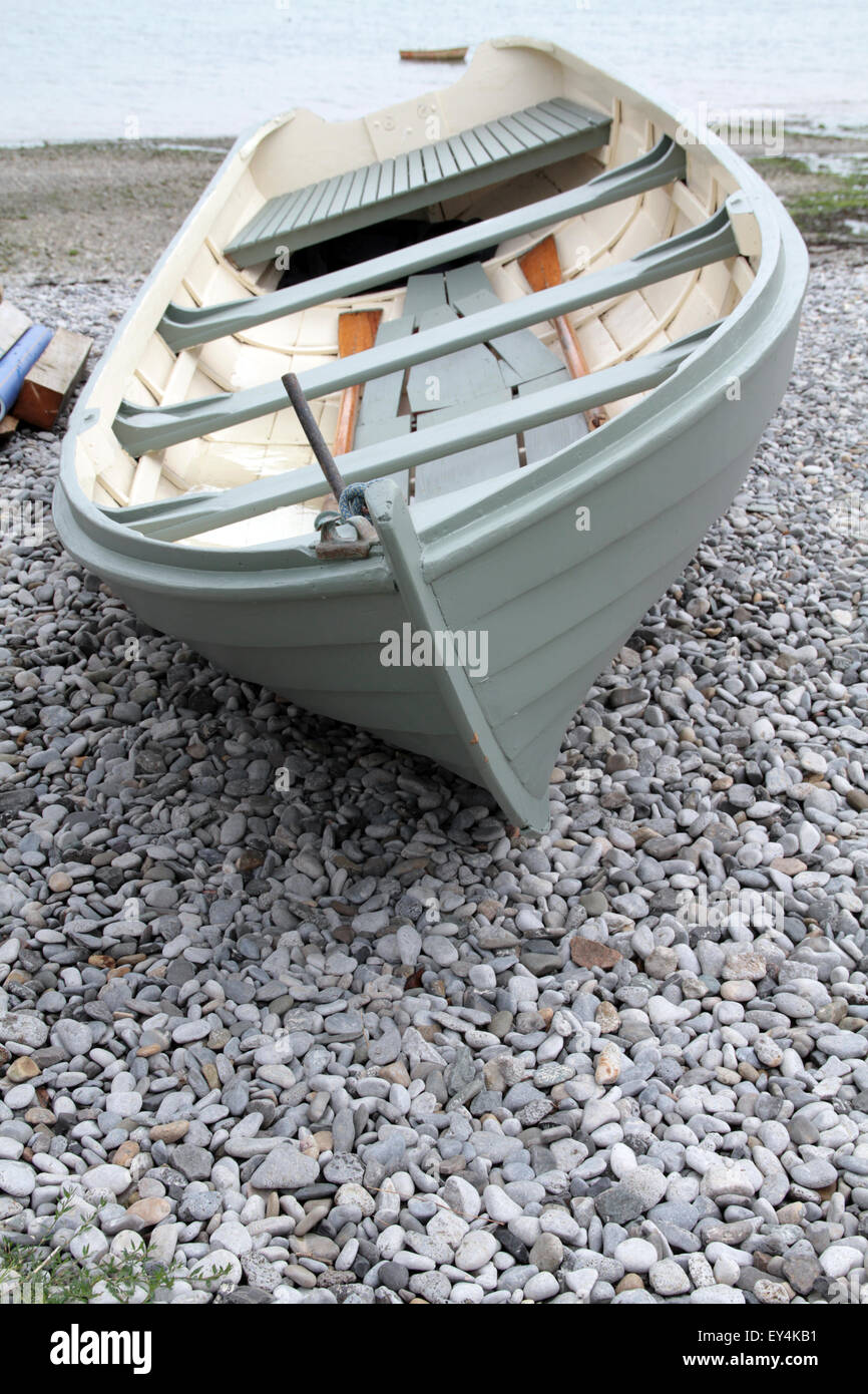 Grey colored rowing boat beached on pebbled beach Stock Photo - Alamy