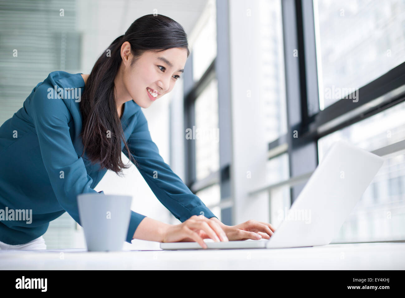 Young businesswoman using laptop in office Stock Photo - Alamy