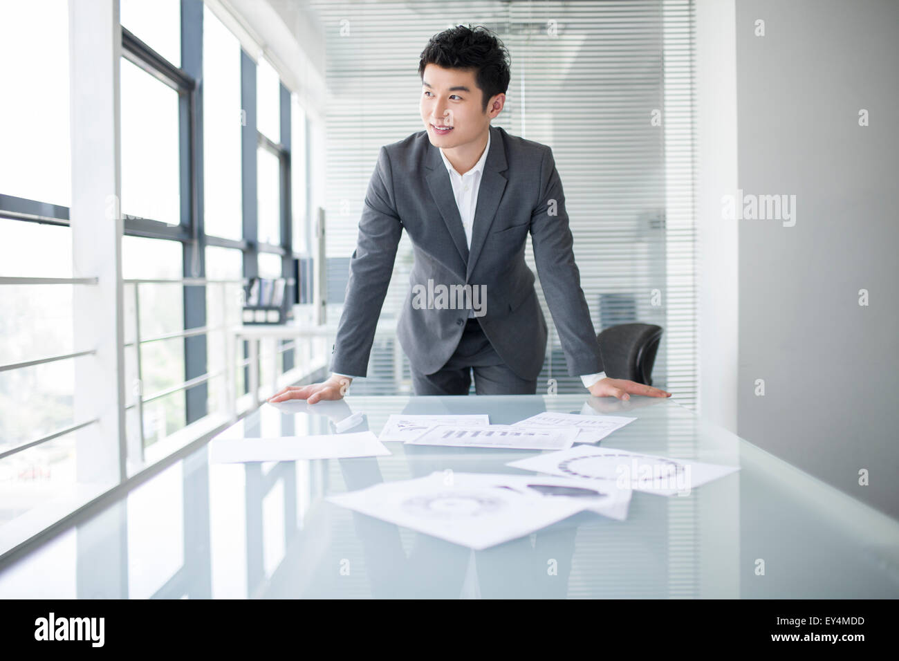 Young businessman looking through window in office Stock Photo - Alamy