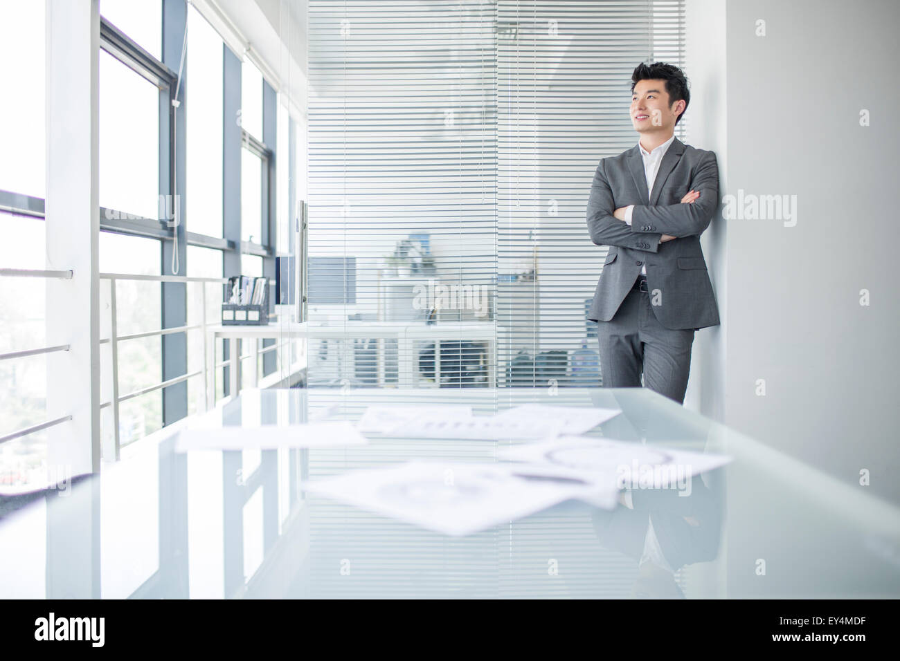 Young businessman looking through window in office Stock Photo - Alamy