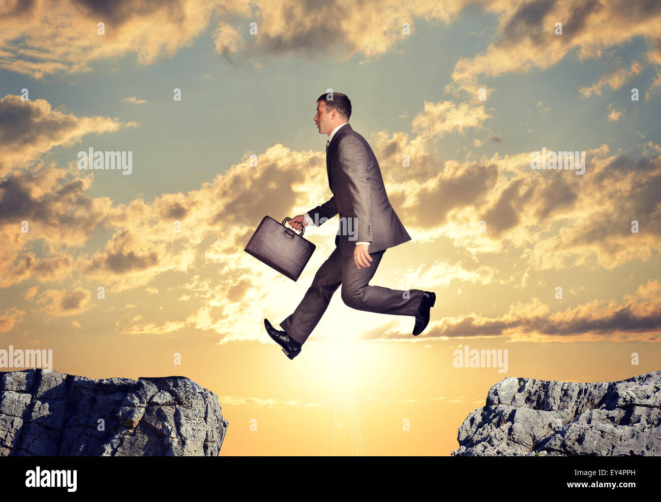 Entrepreneur jumping over abyss Stock Photo - Alamy