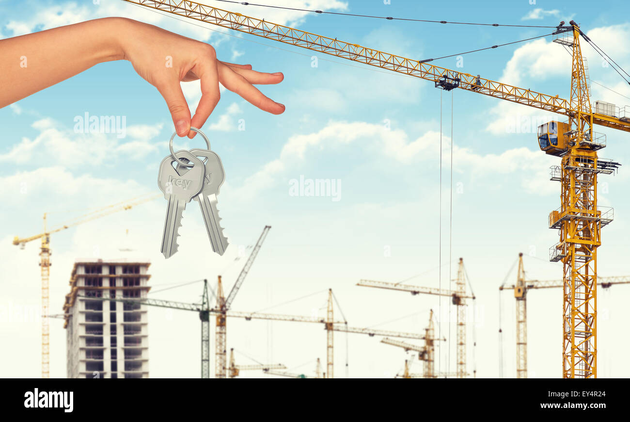 Hand holding keys on construction site background Stock Photo - Alamy