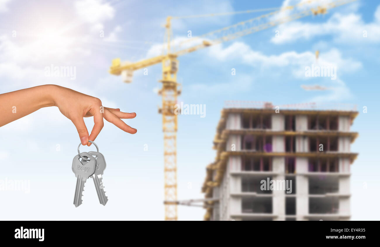 Hand with keys on construction site background Stock Photo - Alamy