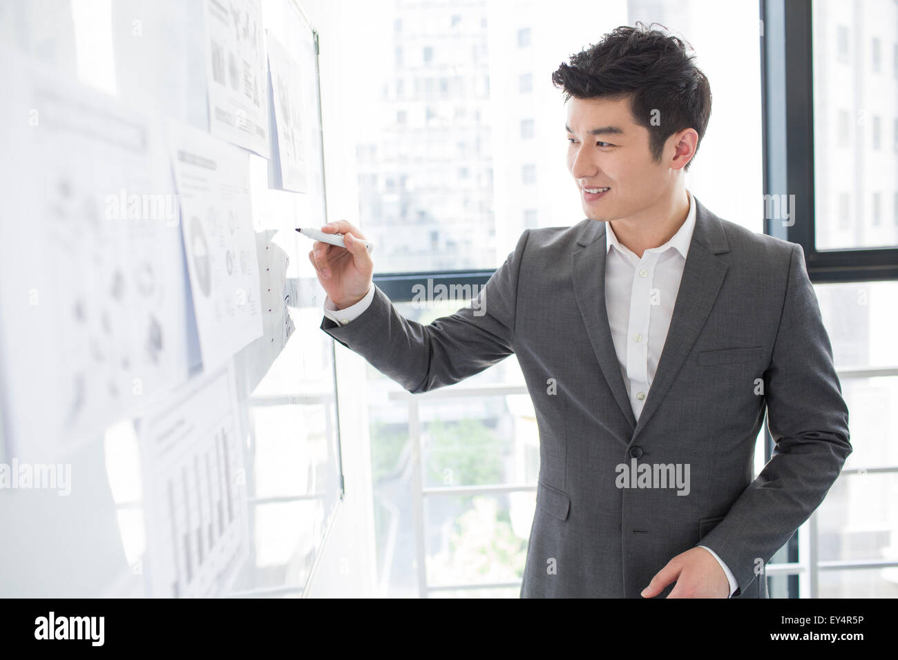 Young businessman writing on whiteboard in office Stock Photo - Alamy
