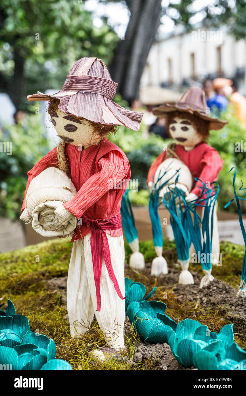 farmers made from corn husks in traditional peasant garb tend rows of ...