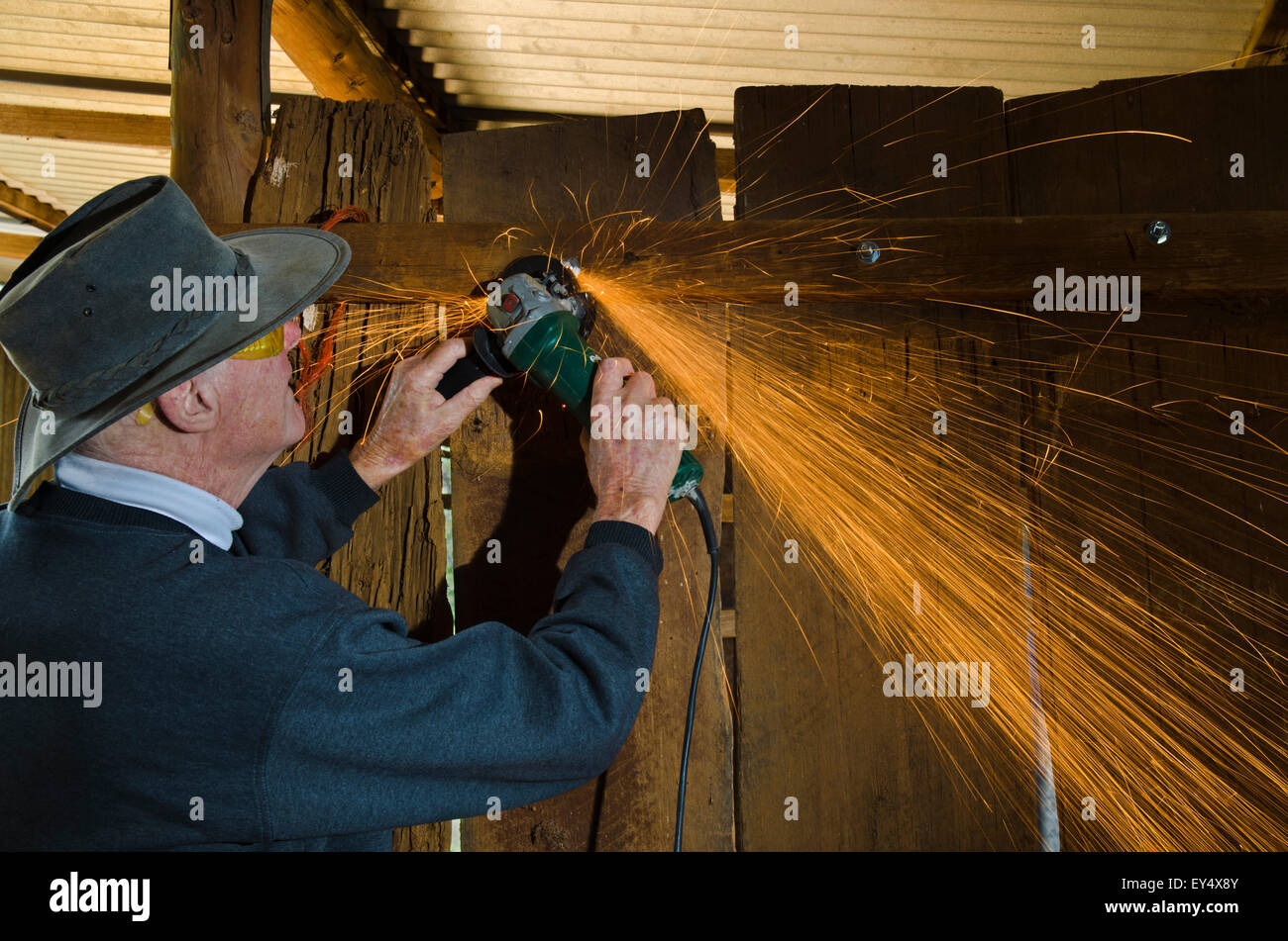 Man using angle grinder producing flying sparks while cutting ...