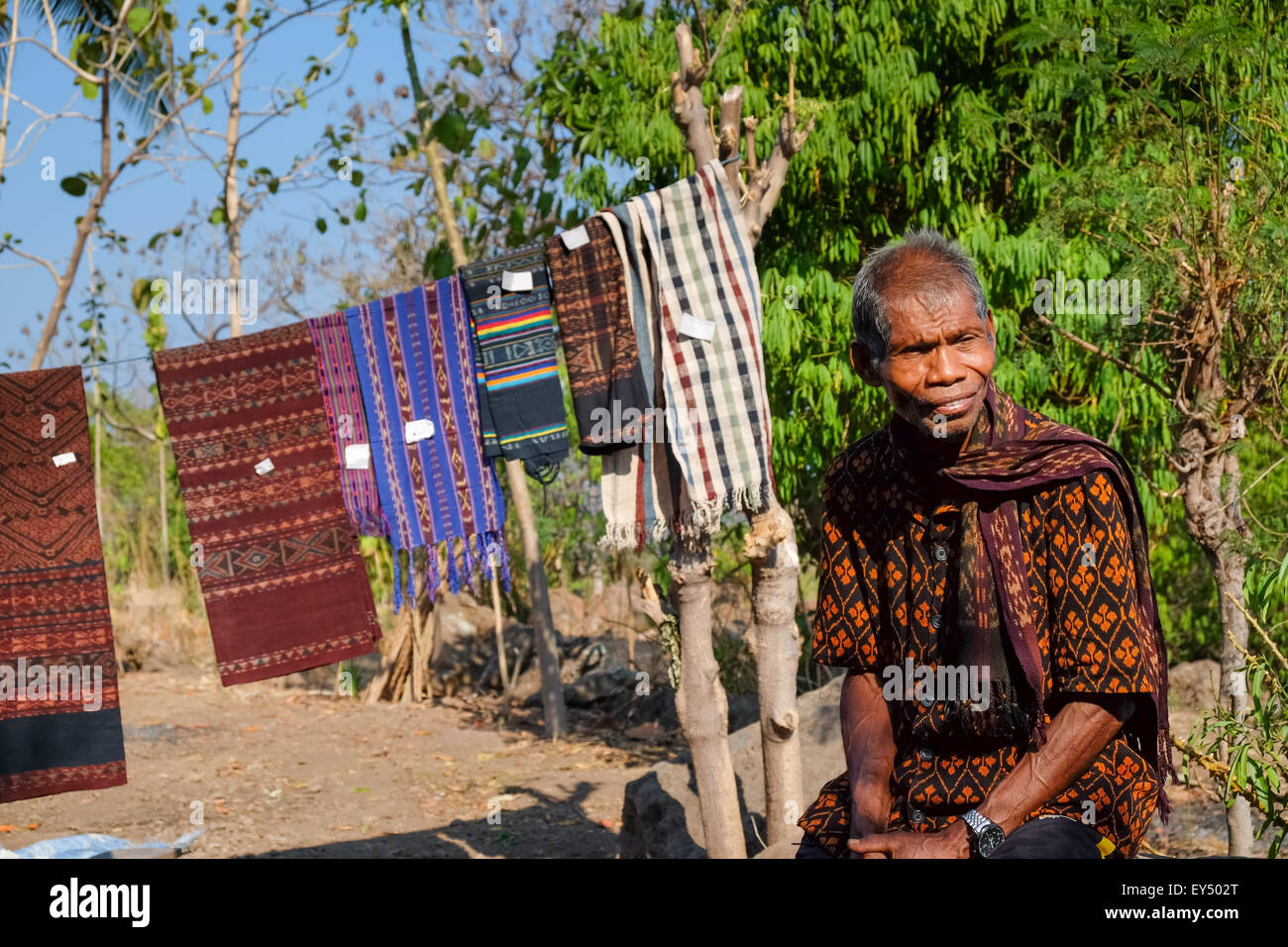 An elder photographed in a background of traditional woven fabrics ...