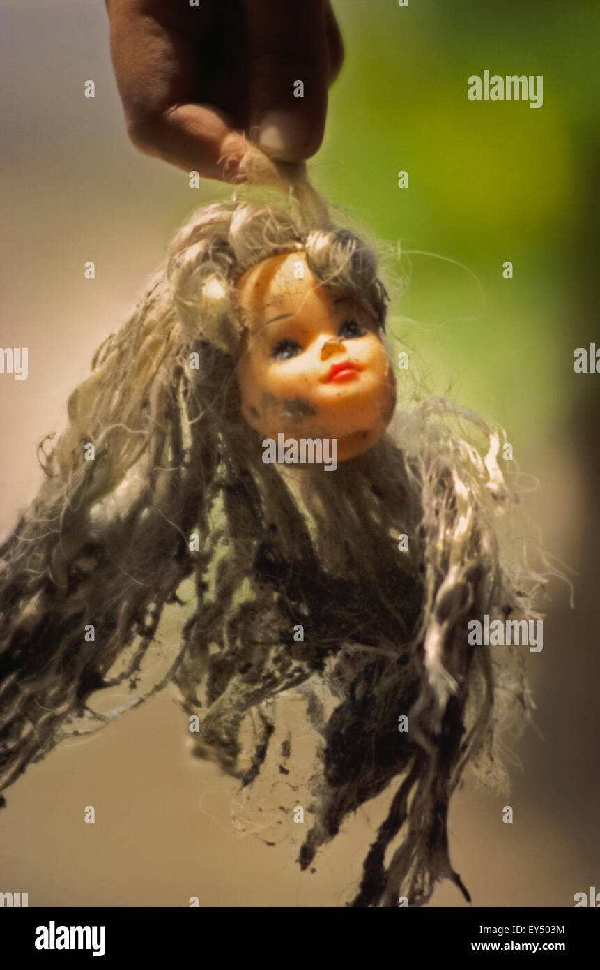 A child holding the head part of a broken doll Stock Photo - Alamy