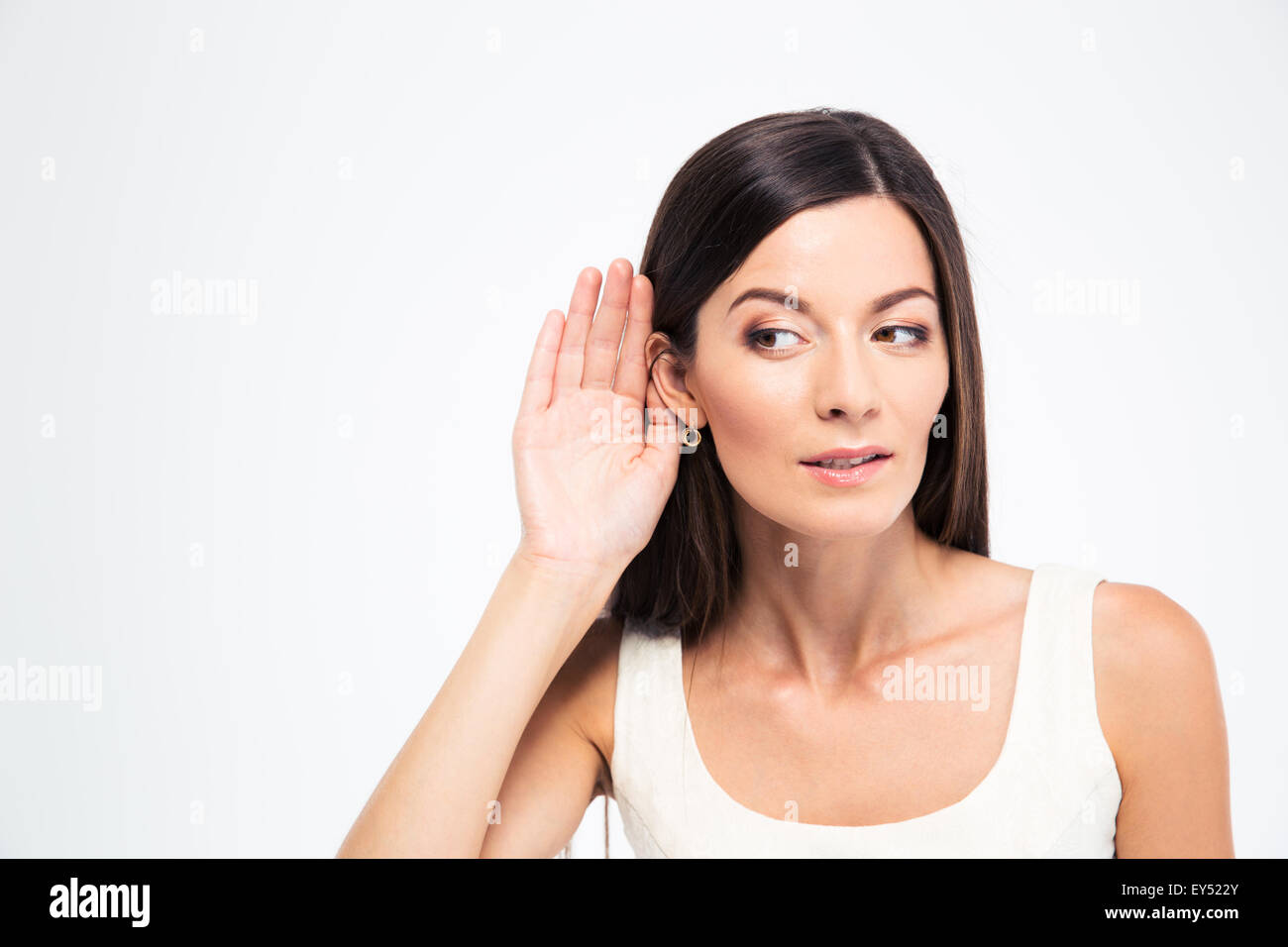 Beautiful woman puts a hand to the ear to hear better isolated on a ...