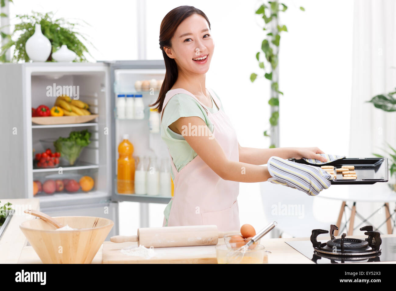 Portrait of young woman cooking in kitchen Stock Photo - Alamy