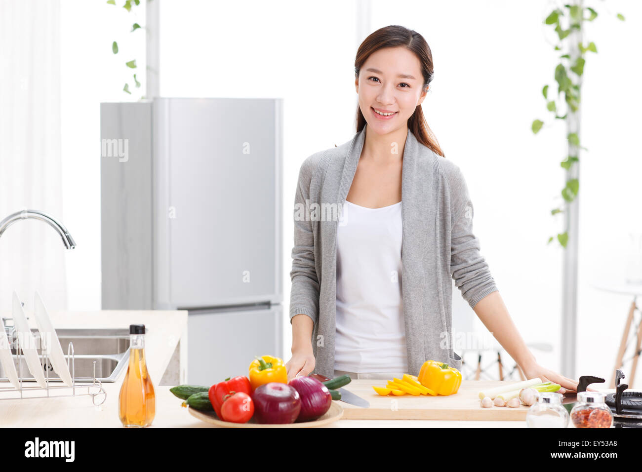 Portrait of young woman preparing food in kitchen Stock Photo - Alamy