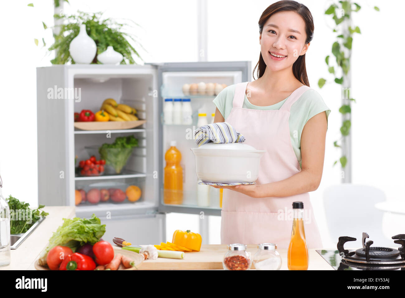 Portrait of young woman cooking in kitchen Stock Photo - Alamy