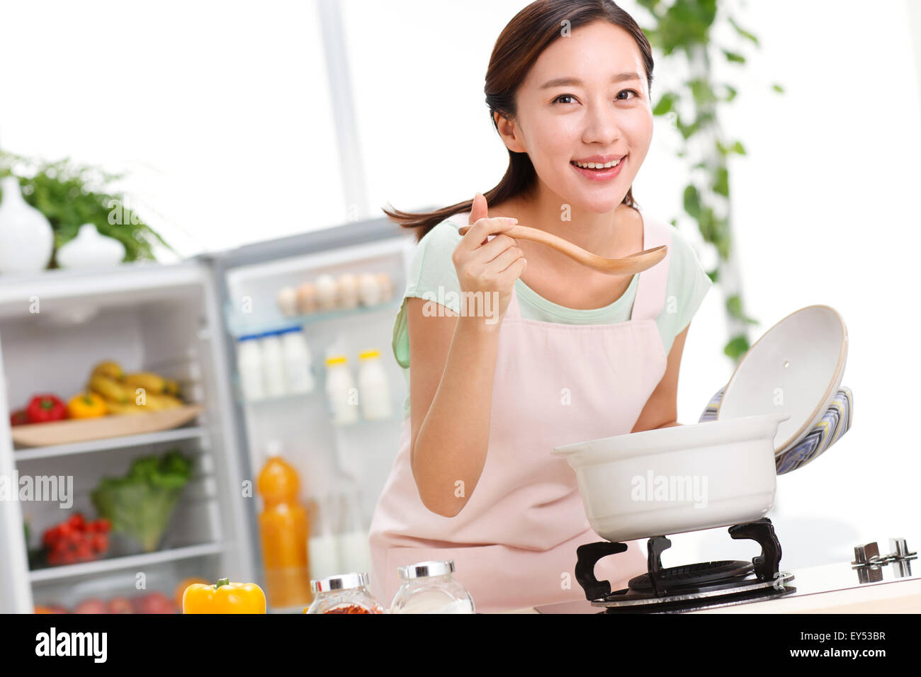 Portrait of young woman cooking in kitchen Stock Photo - Alamy