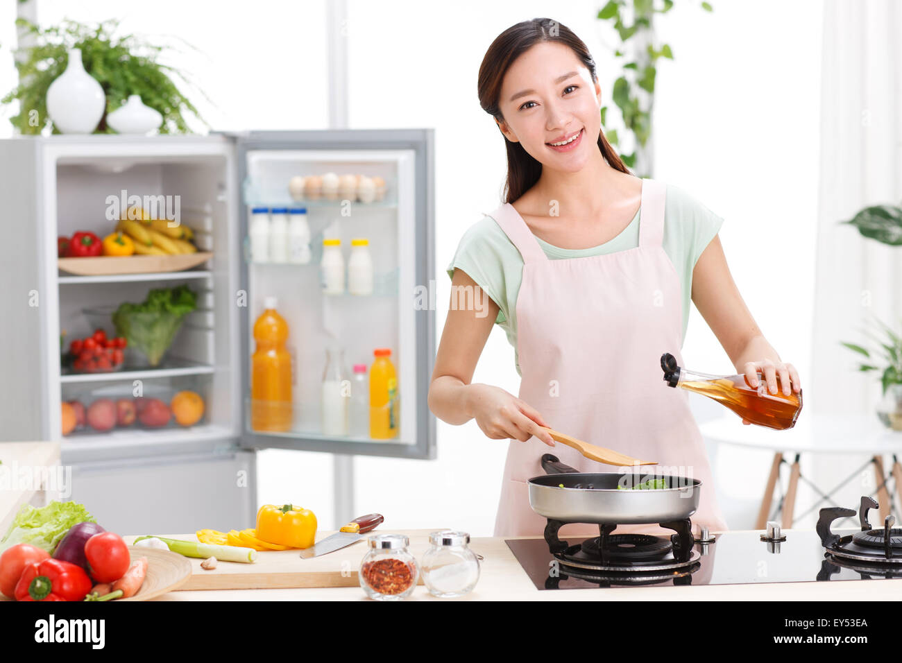 Portrait of young woman cooking in kitchen Stock Photo - Alamy